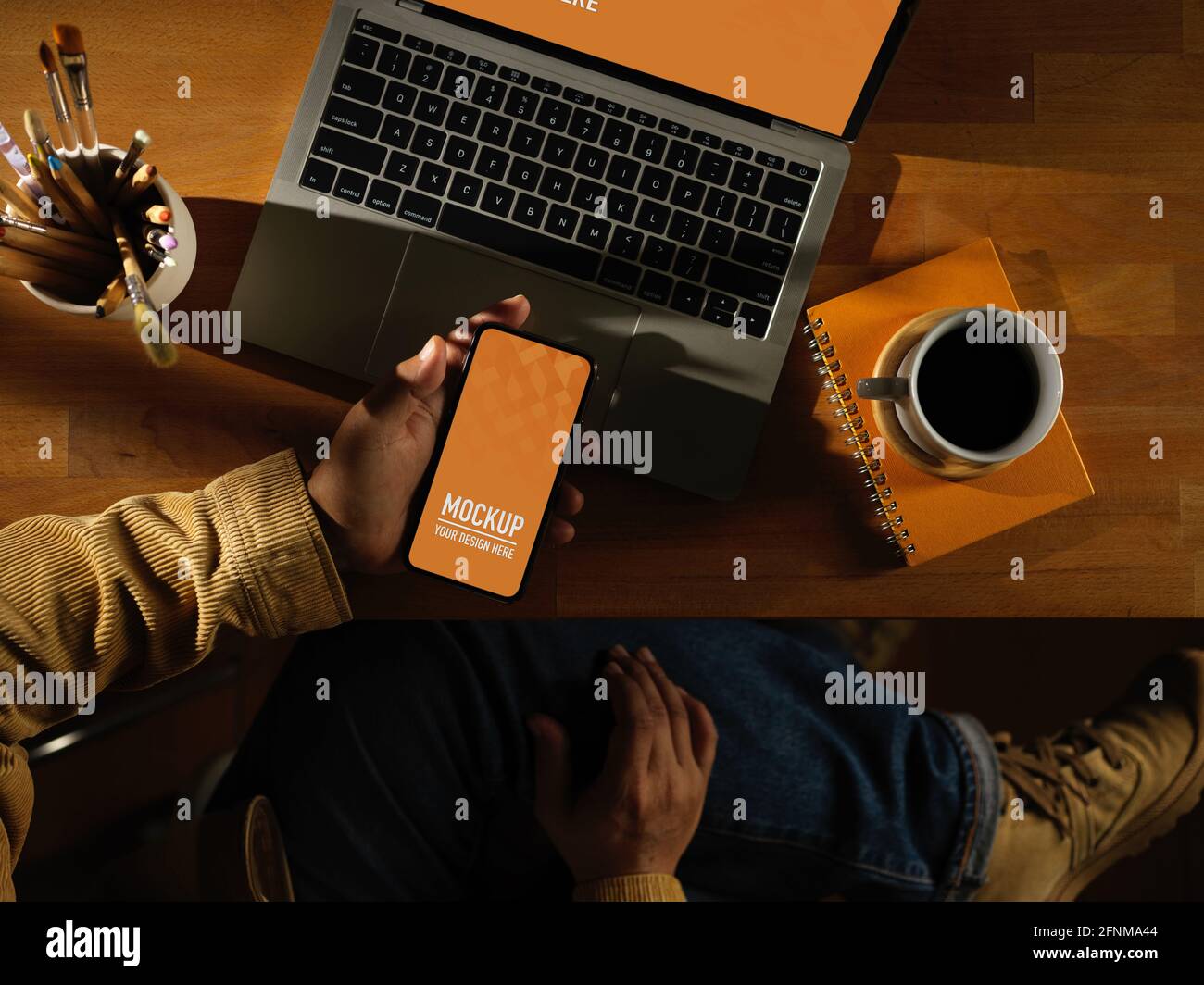 Overhead shot of male hand holding smartphone on wooden office desk ...