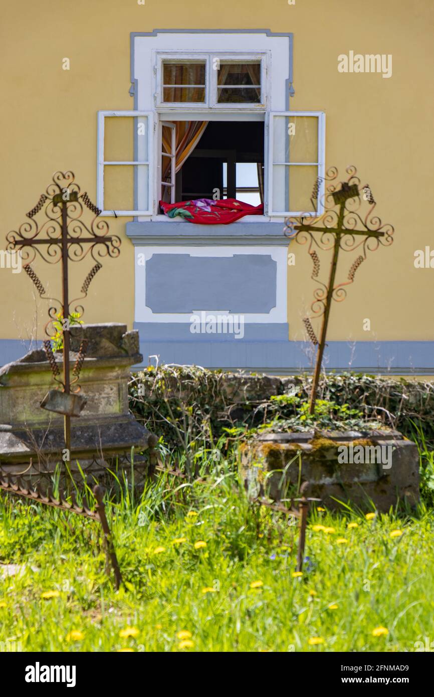 Old crosses on graves under the open window of a building with a ...