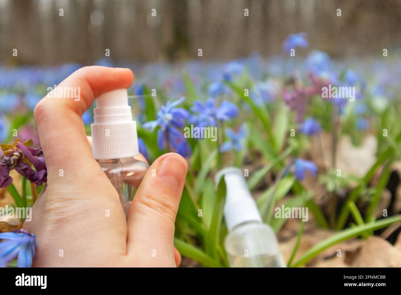 Hand spray clear liquid pump bottle in blooming spring flower lawn of ...