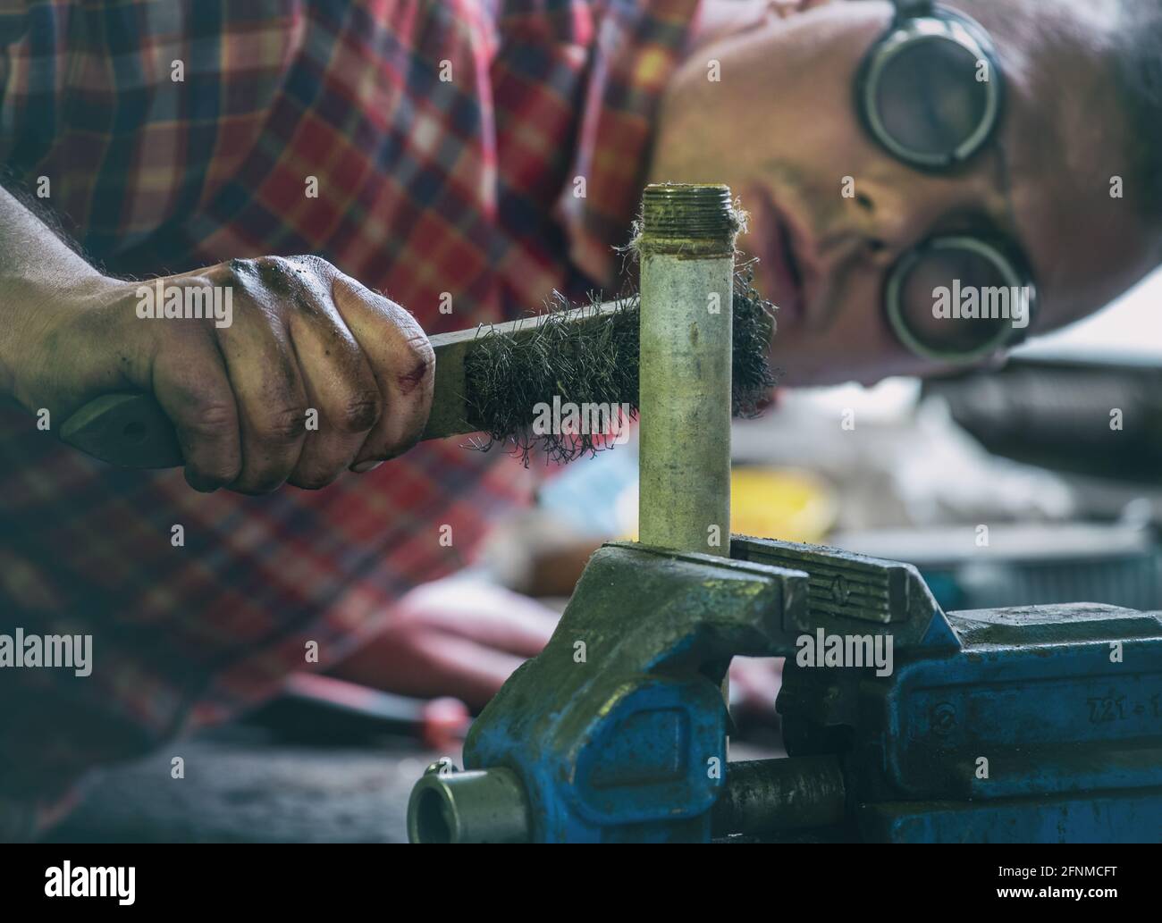 Worker cleaning steel pipe in lathe with wire brush in factory Stock ...