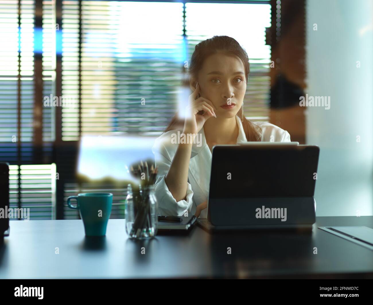 View through glass window of female office worker looking into camera ... View through glass window of female office worker looking into camera ...