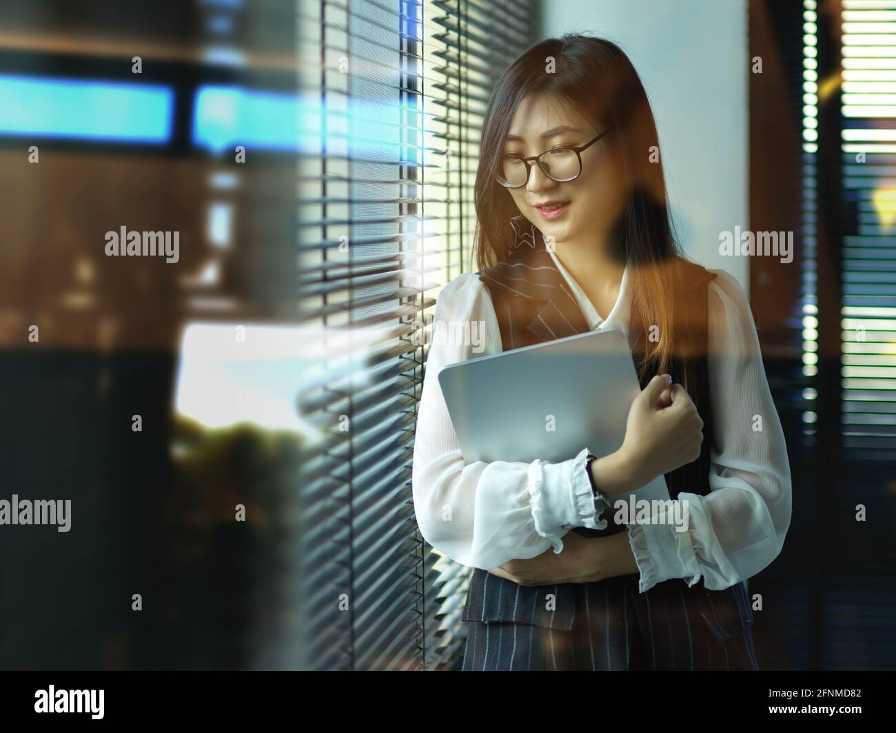 View through glass window of female office worker holding digital ...