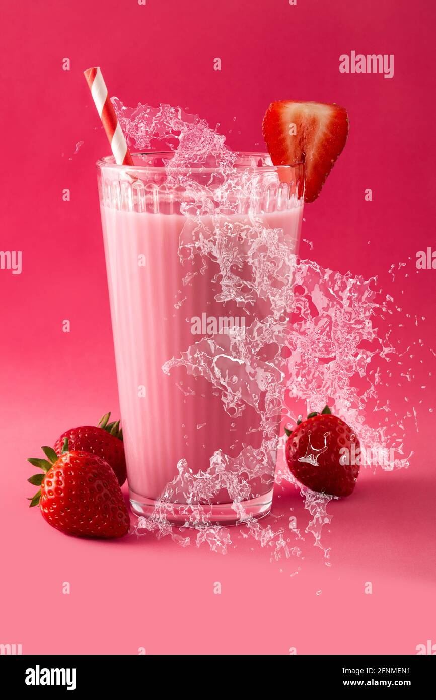 Strawberry milkshake splashing in glass on pink background Stock Photo ...