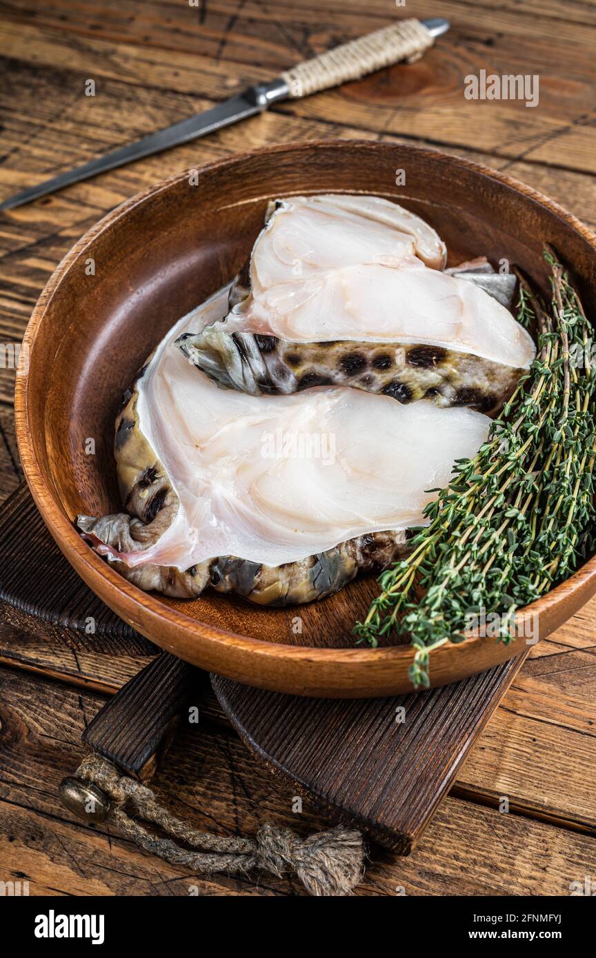 Raw wolffish or wolf fish fillet in a wooden plate. wooden background ...