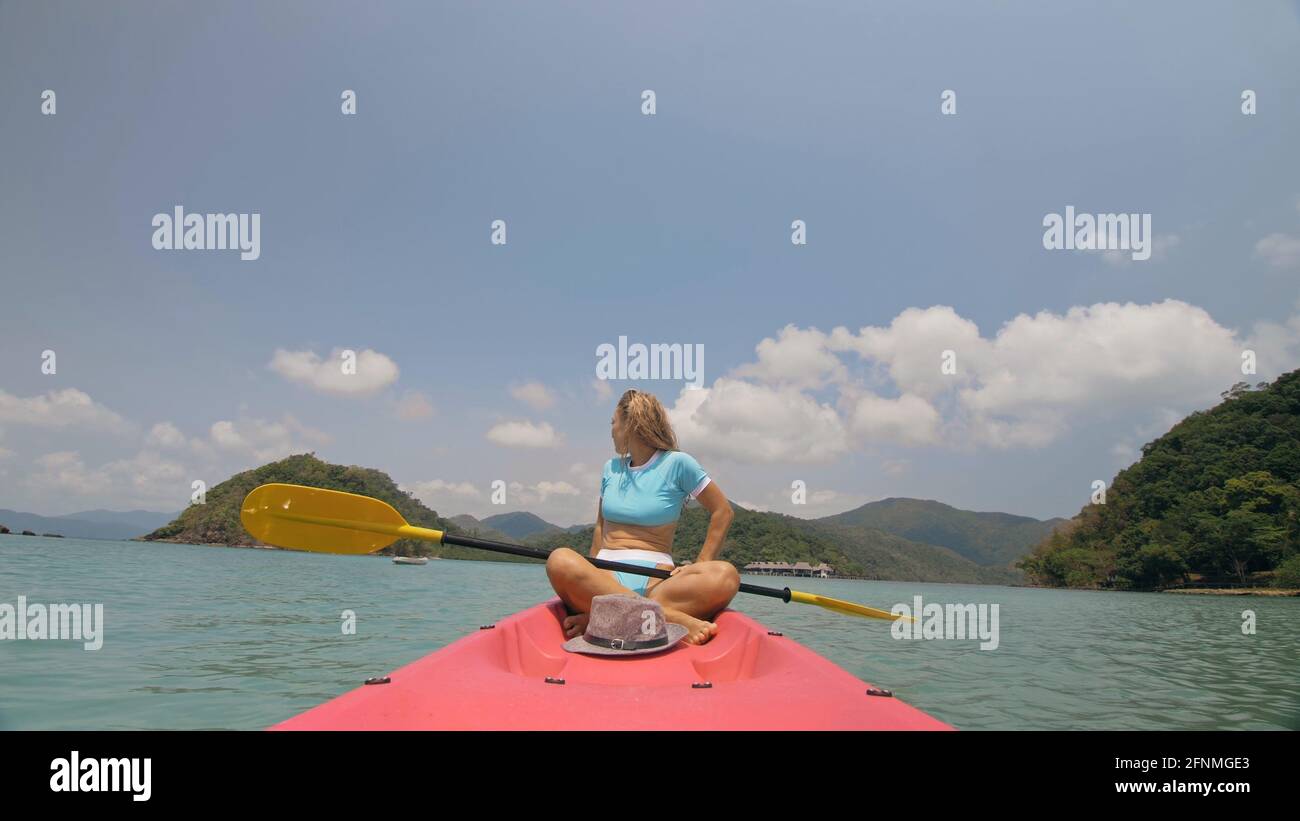 Sportive woman rows pink plastic canoe along sea water. Positive sports ...
