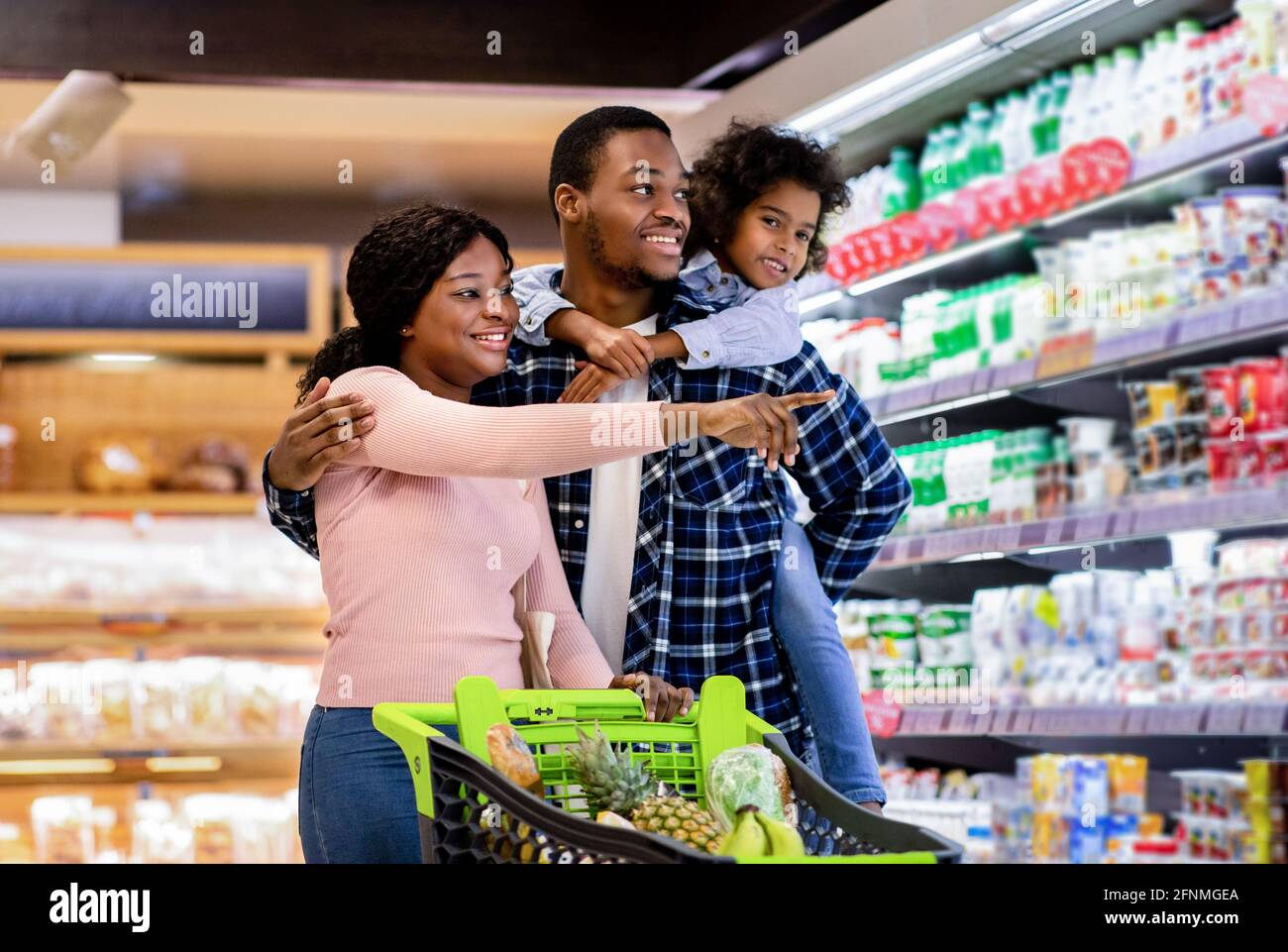 Family shopping. Young black parents with their cute daughter selecting ...