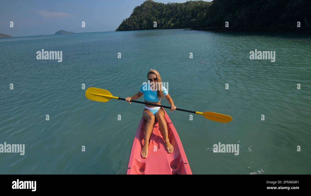 Pretty sportive blonde lady in stylish swimsuit sails on pink plastic ...