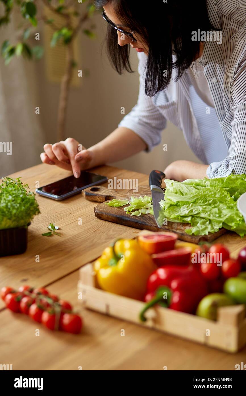 Woman is cooking in the kitchen at home, using digital tablet or ...