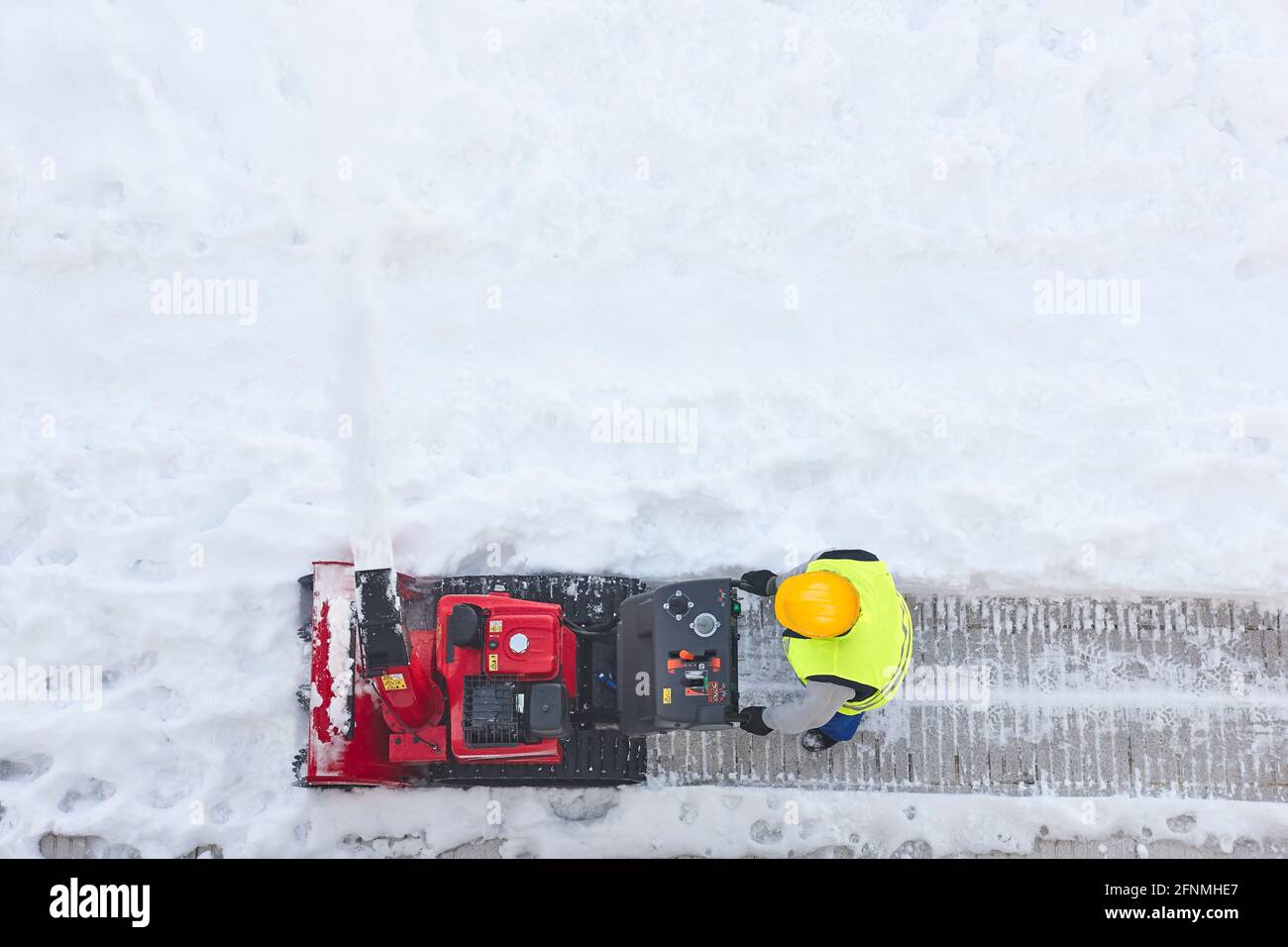Worker cleaning snow on the sidewalk with a snowblower. Maintenance ...