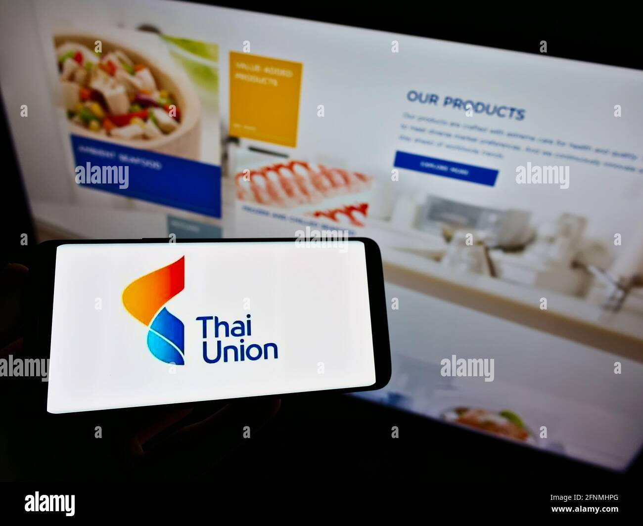 Person holding smartphone with logo of seafood company Thai Union Group ...