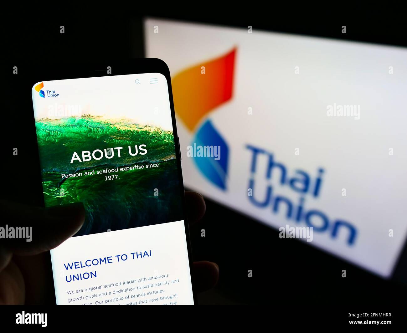 Person holding mobile phone with webpage of seafood company Thai Union ...