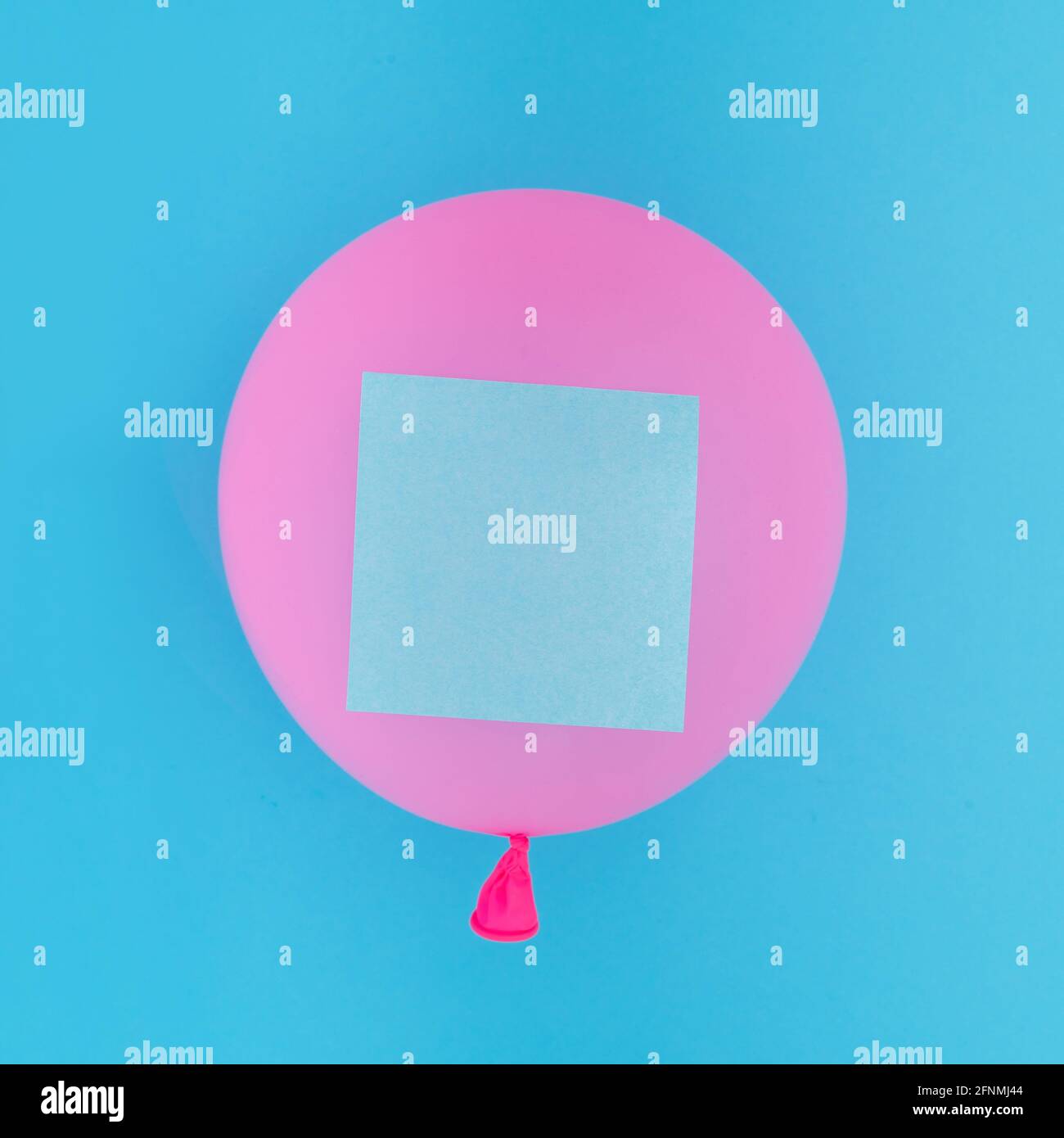 Pink balloon with a sticky note for copy space on a pastel blue ...