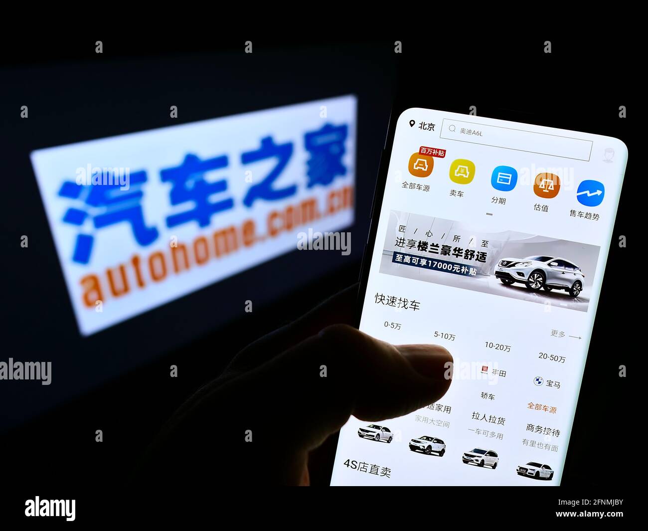 Person holding smartphone with web page of Chinese car trading platform ...