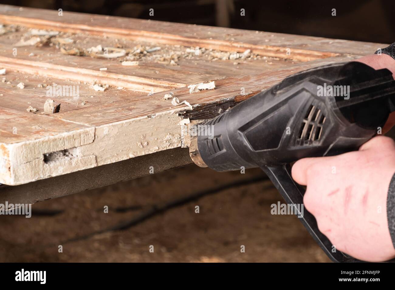 cleaning doors from old paint with a spatula warming up the surface ...