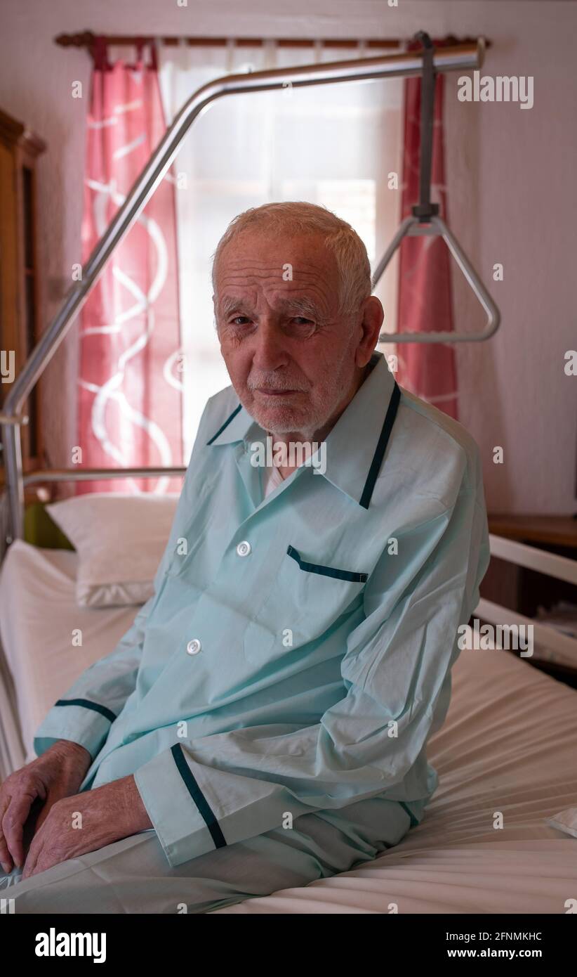 Old man in 80's sitting in medical bed in hospital. Geriatric and ...