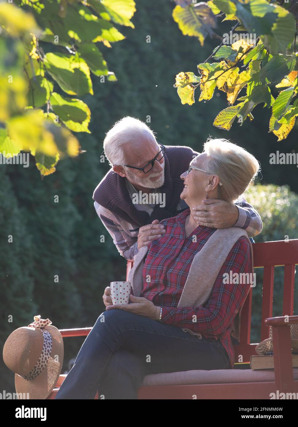 Senior man and woman hugging in garden on autumn sun Stock Photo - Alamy