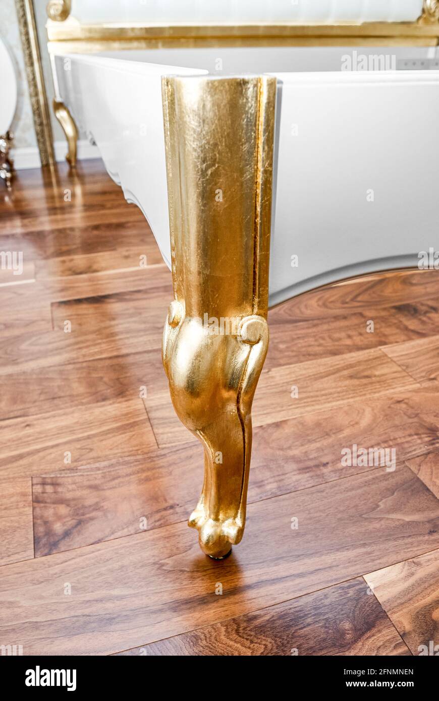 Stylish antique turning leg of bed covered with shiny golden paint on ...