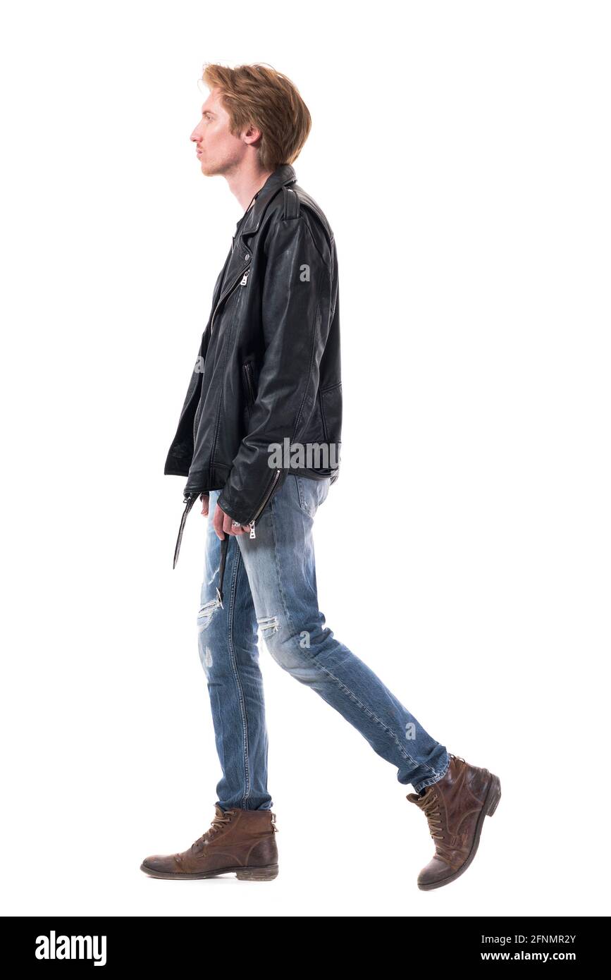 Side view of walking young man in leather jacket and jeans with boots ...