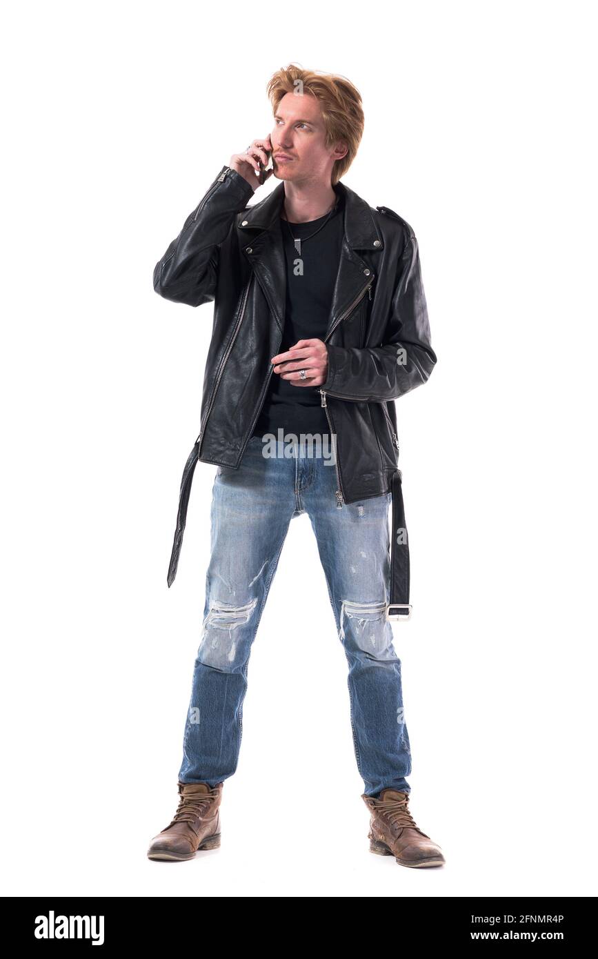 Attentive young biker or rocker redhead male listening cell phone call ...