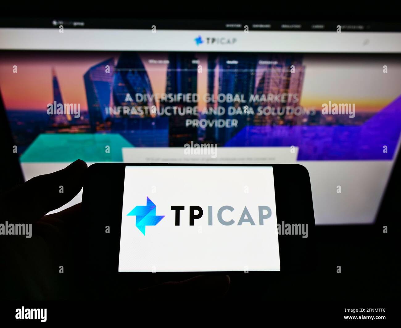 Person holding cellphone with logo of British financial services company TP ICAP Group plc on ...
