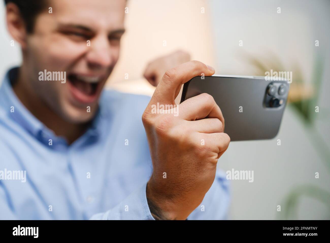 Happy young businessman using smartphone and celebrating success at ...
