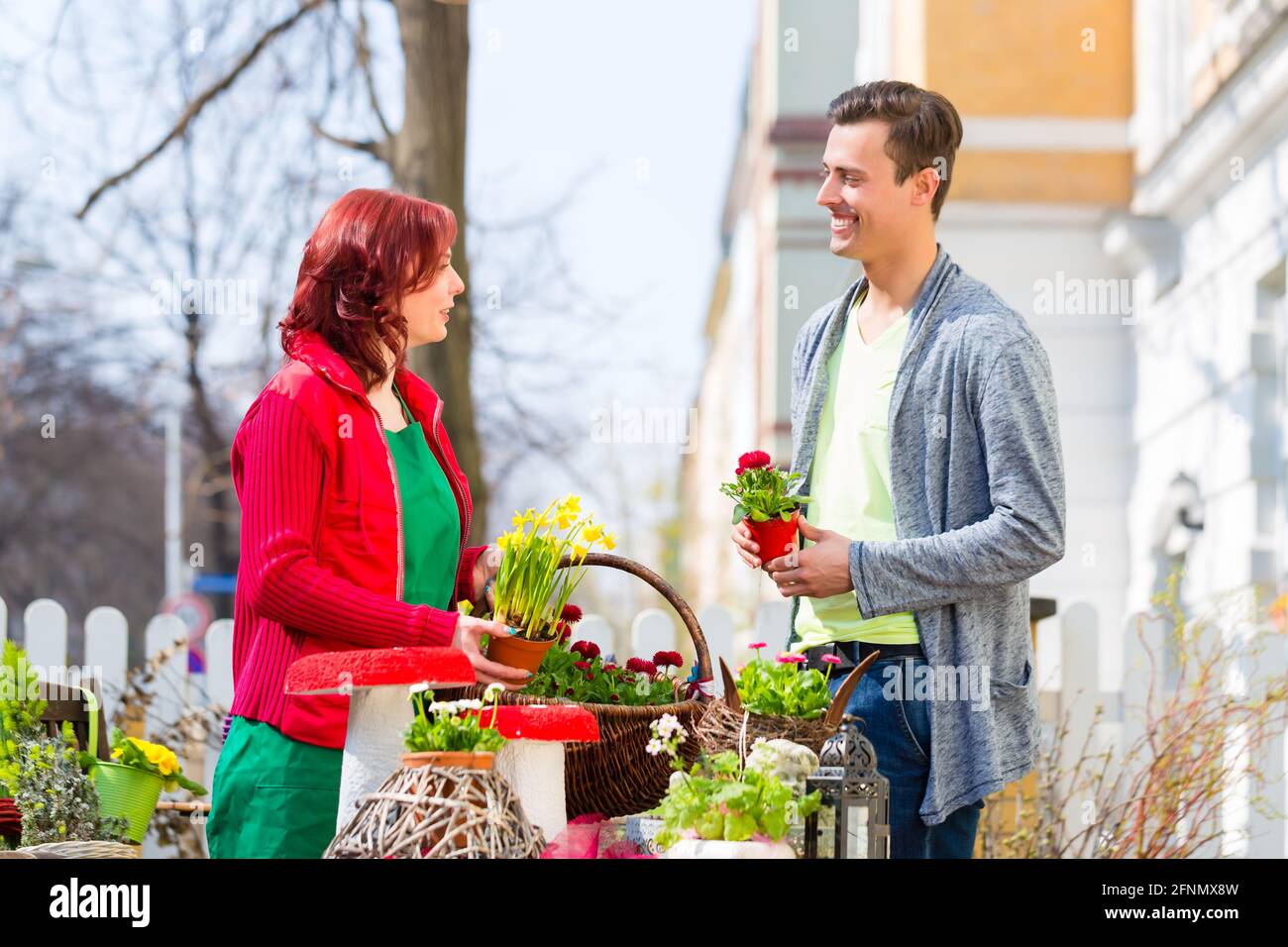 Female florist selling man plant in front of flower shop Stock Photo ...