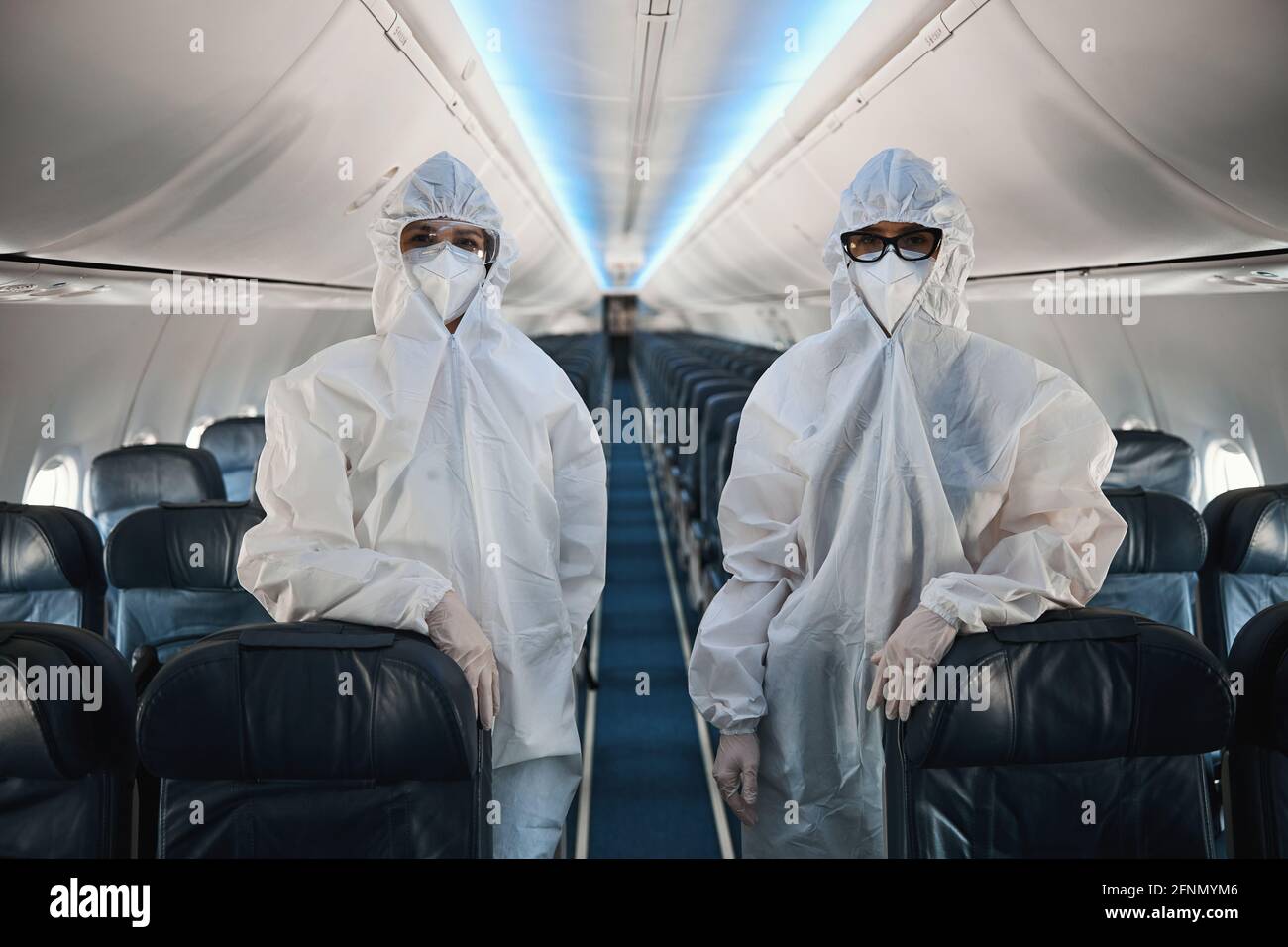 Two cabin crew workers in protective overalls in plane cabin Stock ...