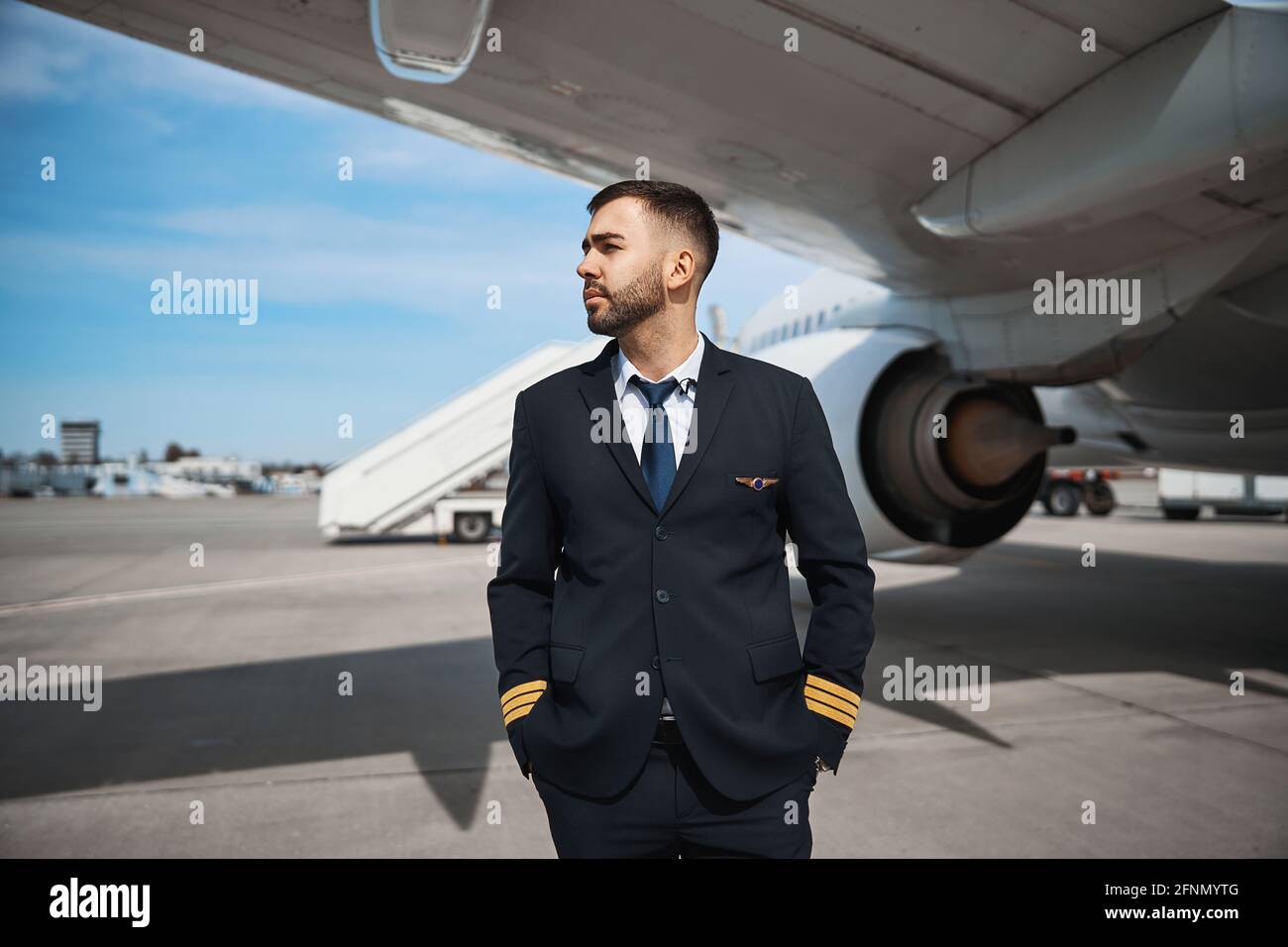 Self-assured pilot near airplane turning his head to the left Stock ...