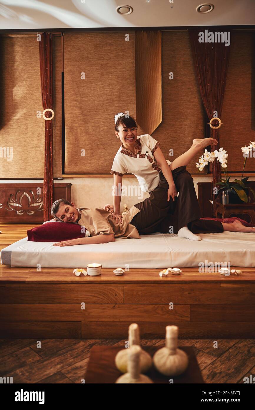 Thai female spa worker doing leg stretches for client Stock Photo - Alamy