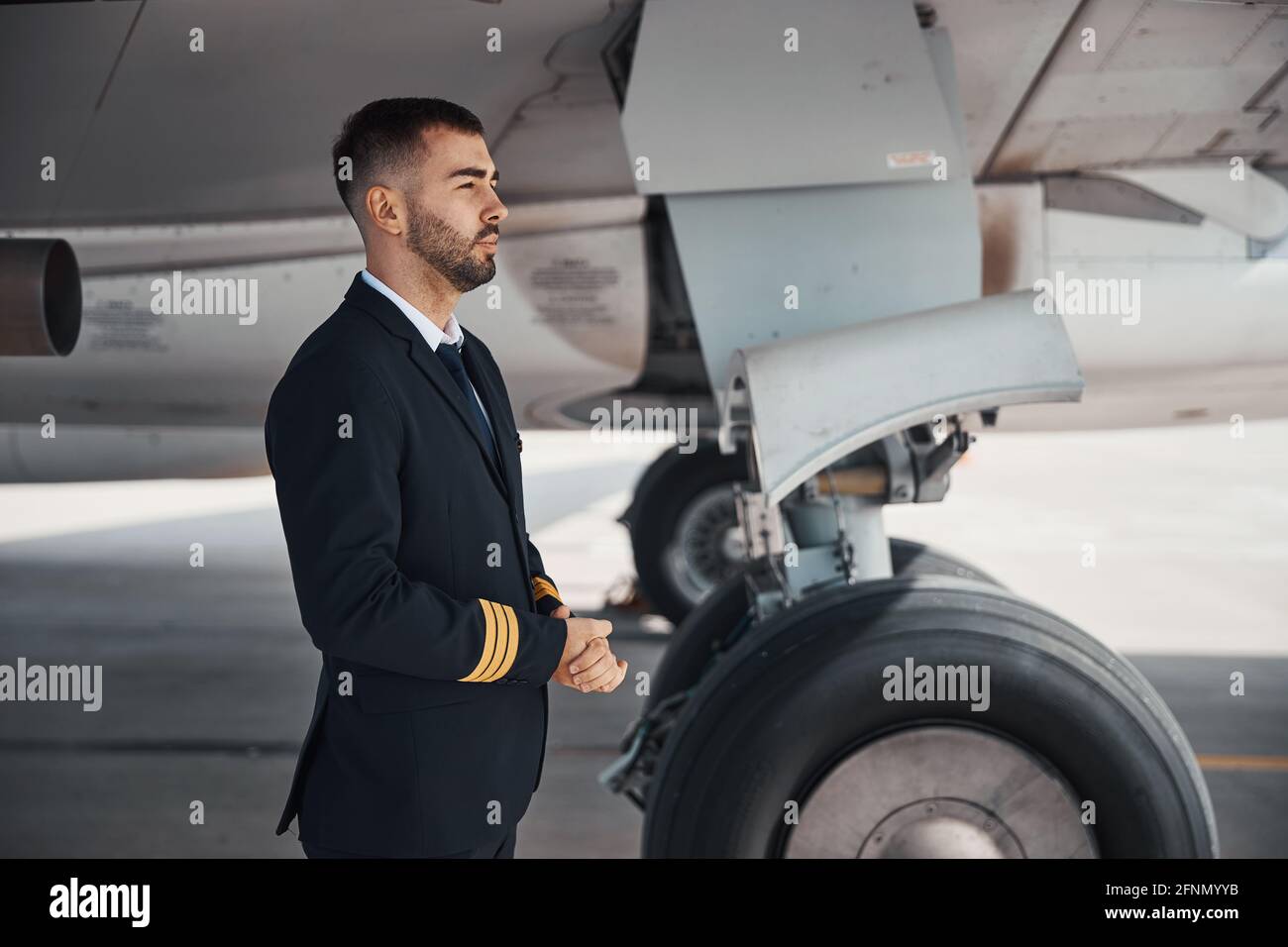 Professional pilot joining hands near plane landing gear Stock Photo ...