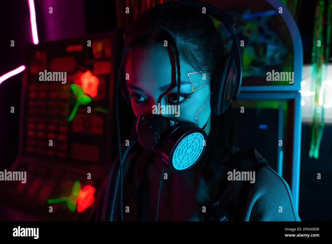 young asian woman with scar in gas mask and wireless headphones looking ...