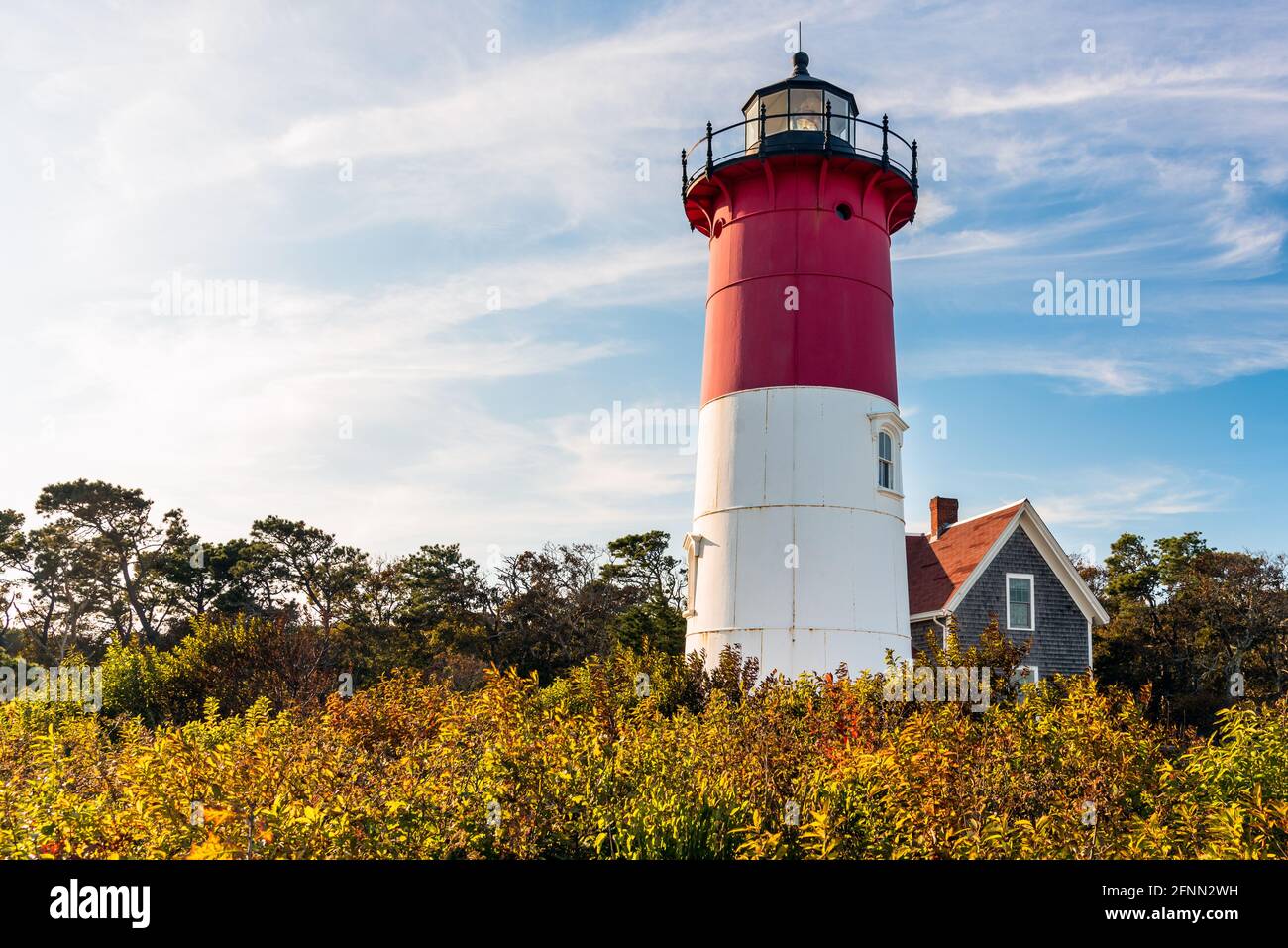 Historic white and red lighthouse under cloudy sky with patches of blue ...