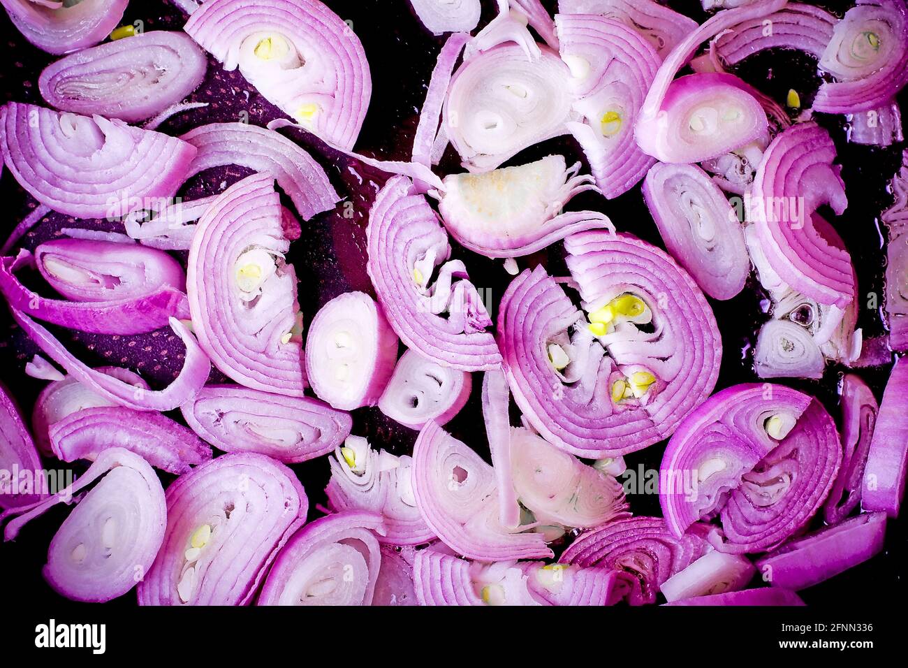 Red onion cut into pieces in a black pan Stock Photo - Alamy