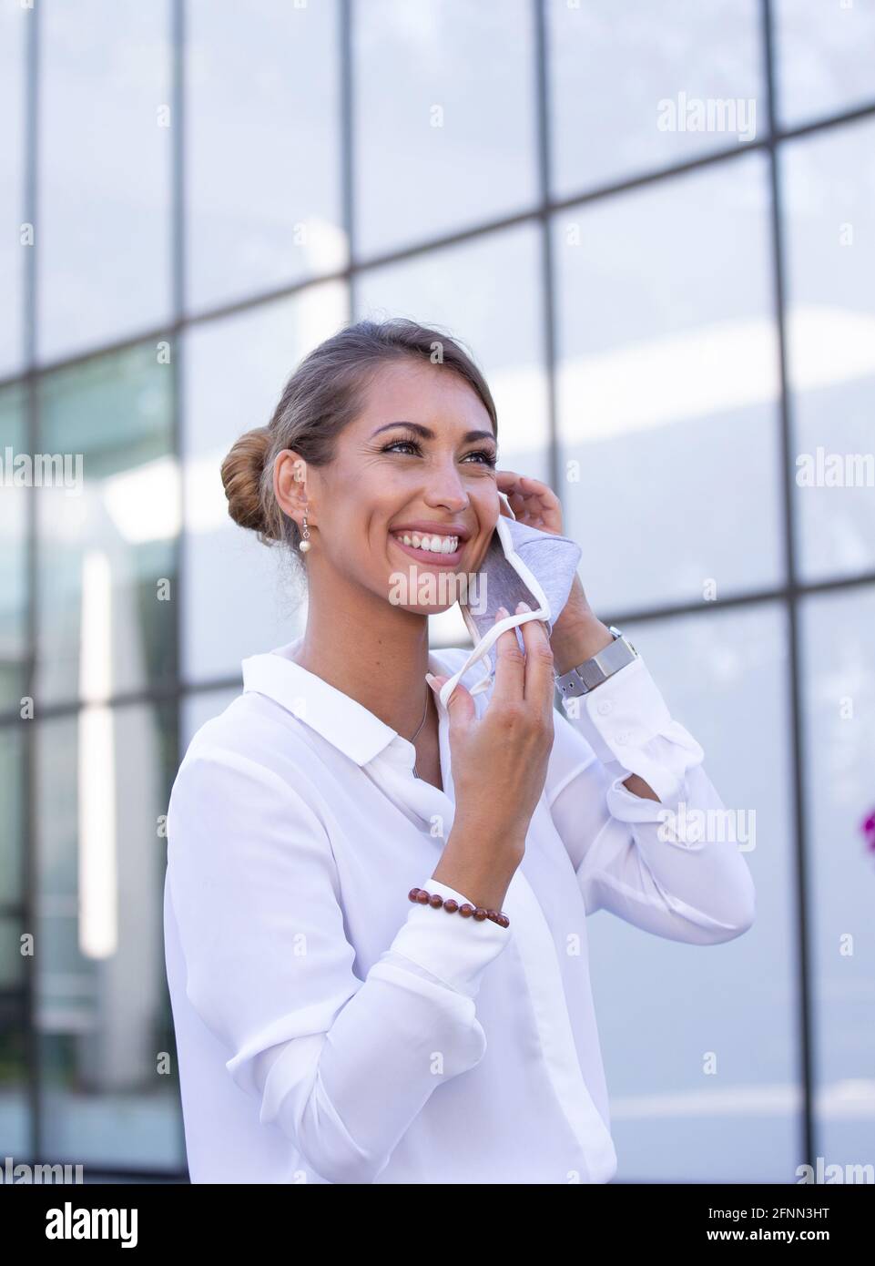 Pretty young business woman putting protective mask on in front of ...
