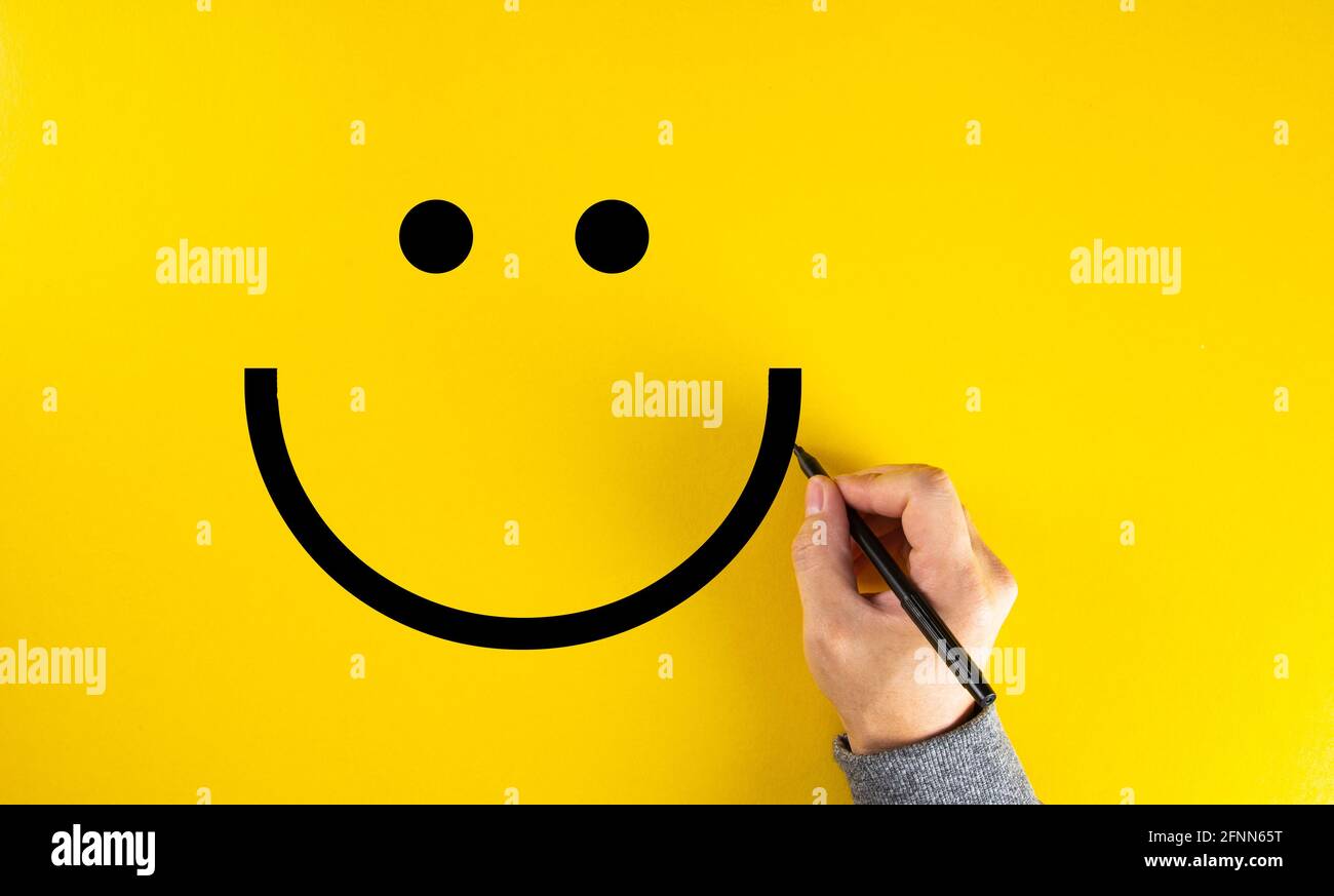 Male hand drawing a smiling happy face sketch on yellow background ...