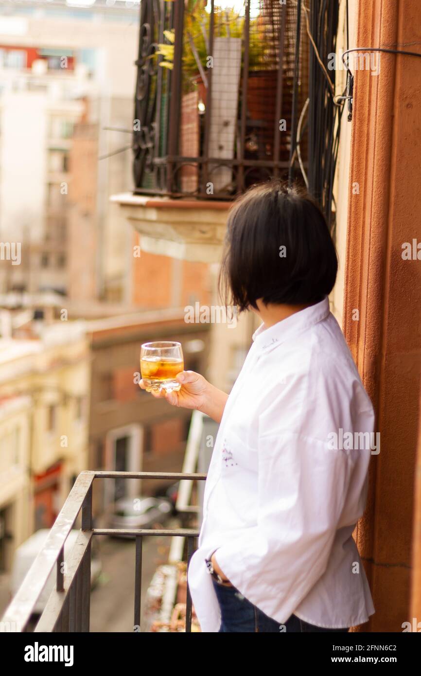 Vertical shot of a Hispanic female drinking a glass of cognac on the ...