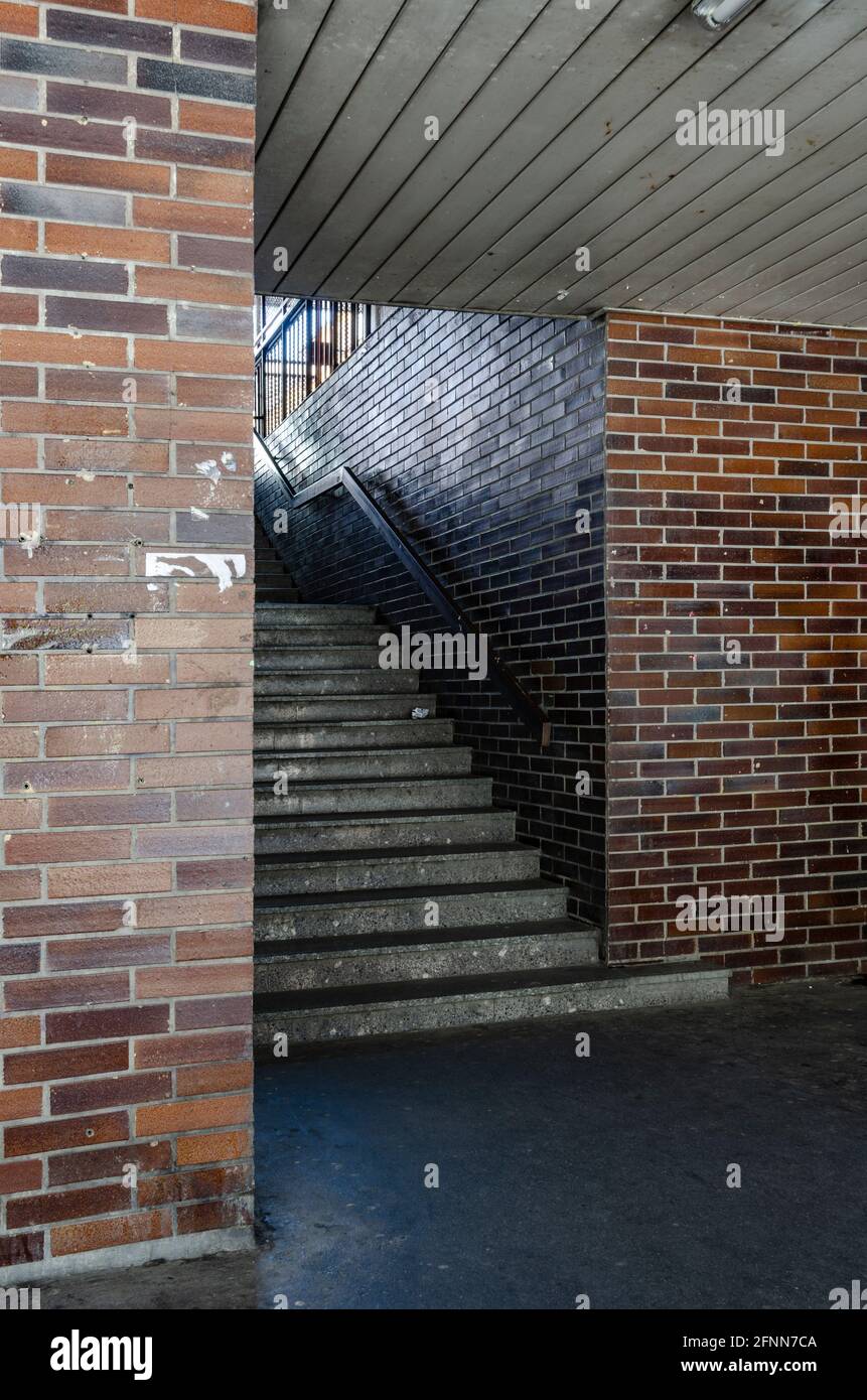 A void passage with a dark staircase and a wall with worn brown glazed ...