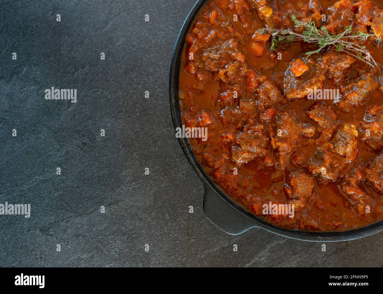 mediterranean beef stew alla bolognese in a rustic iron pan on dark ...
