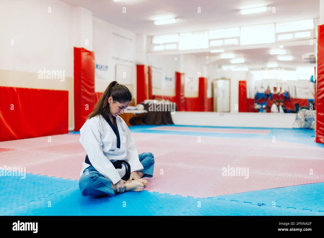Young woman stretching in a dojo wearing taekwondo dobok Stock Photo ...