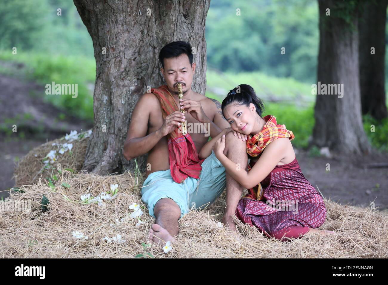 Couple love of Asian Young man and women sitting under tree against buffalo and natural ...