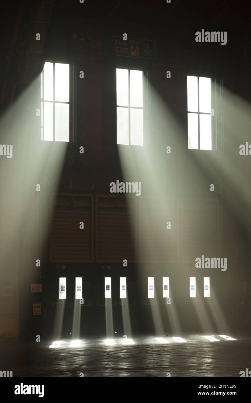 Atmospheric sunbeams streaming through the the windows of a large old ...