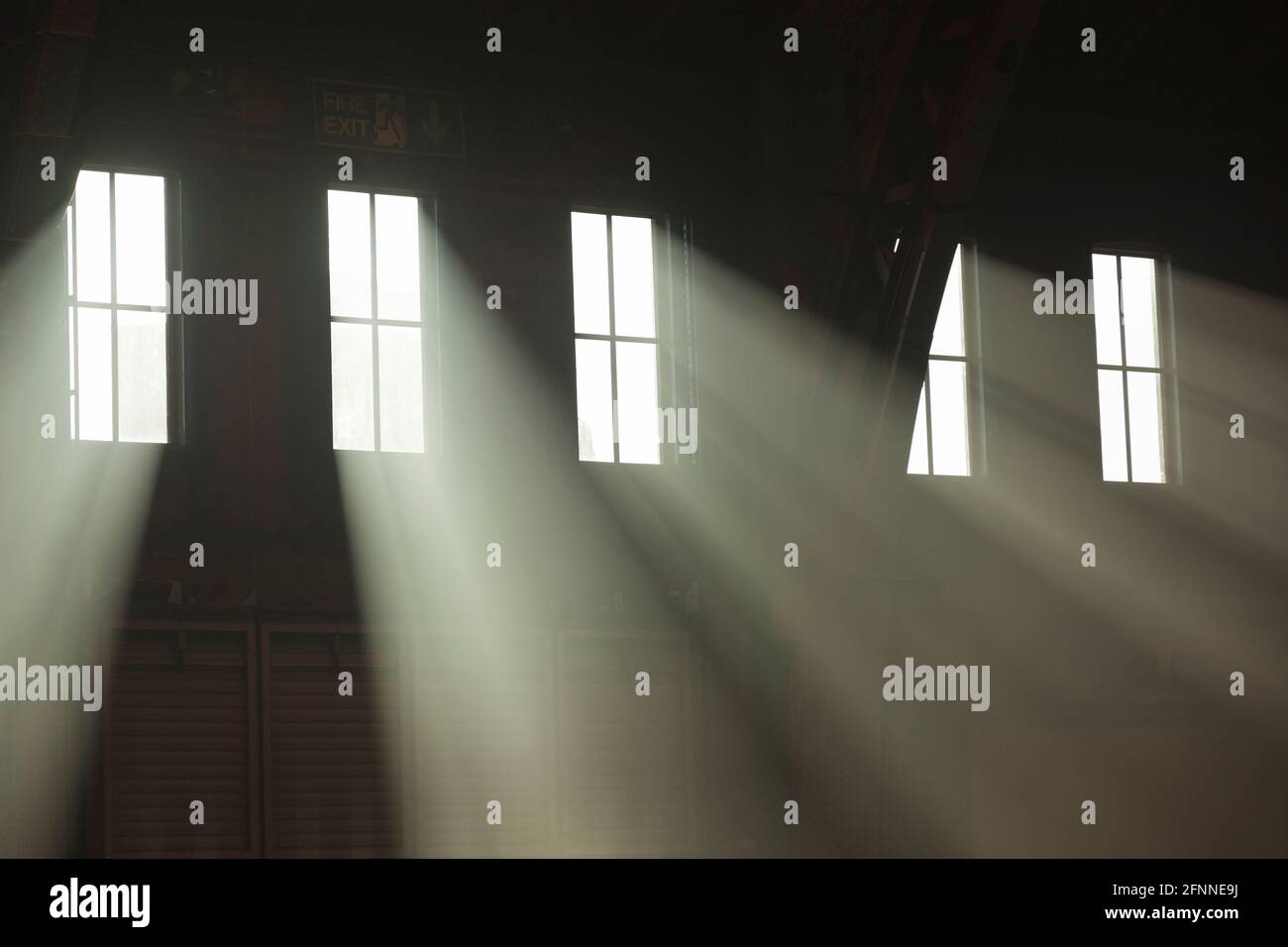 Atmospheric sunbeams streaming through the the windows of a large old ...