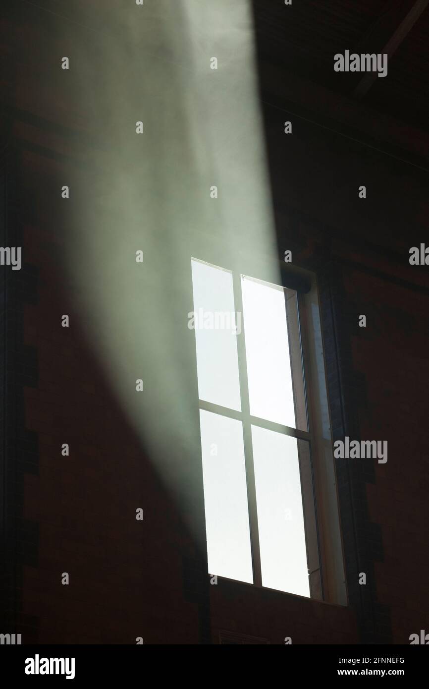 Atmospheric sunbeams streaming through the the windows of a large old ...