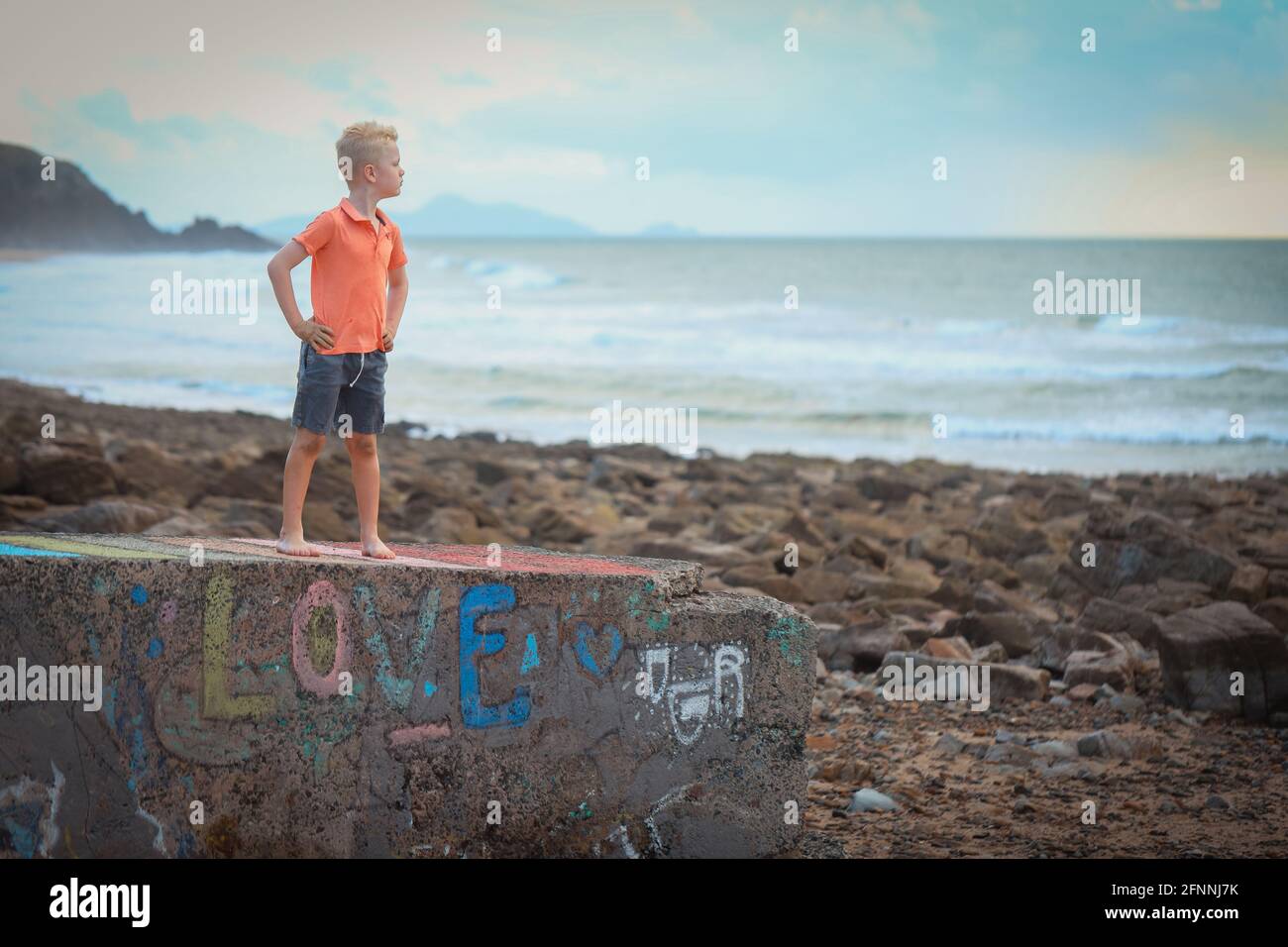 Scenic view of a white Caucasian young boy staring at the blue ocean ...