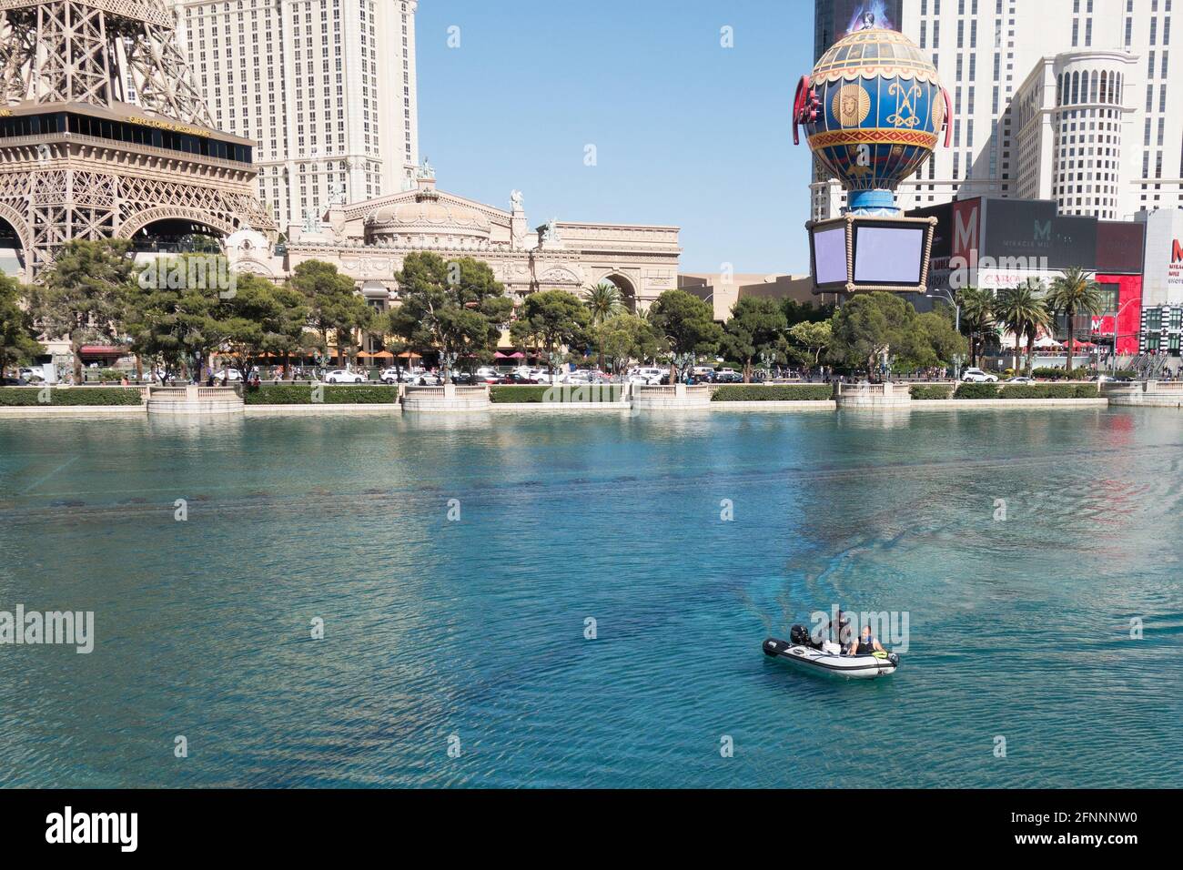 Two men in a small raft cleaning trash out of the fountain of the ...