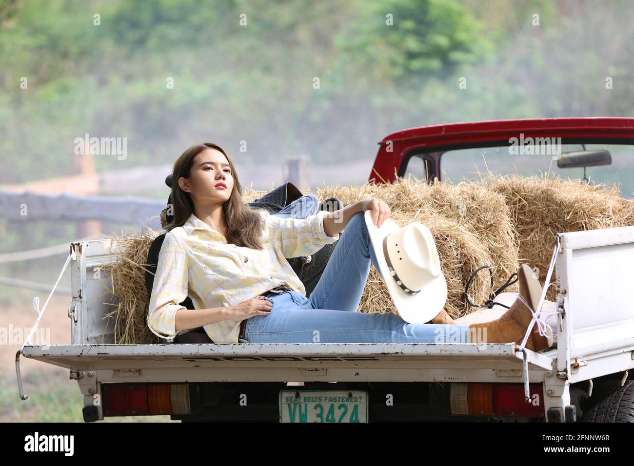A woman in a cowgirl style sits in a horse ranch with a western farm ...