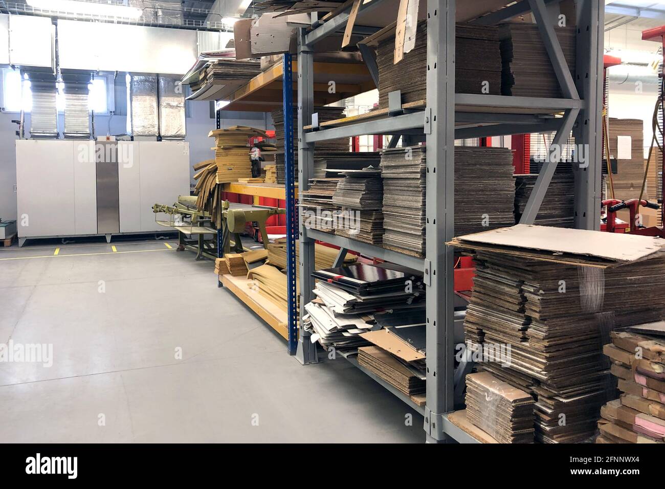 Carton factory or storage with pallets, shelves and stacks of paper and ...