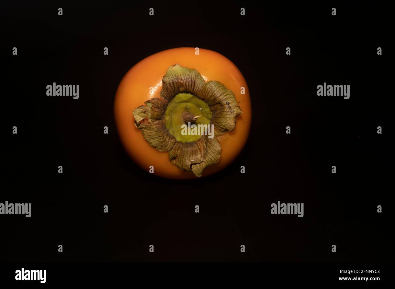 Single persimmon black background Stock Photo - Alamy