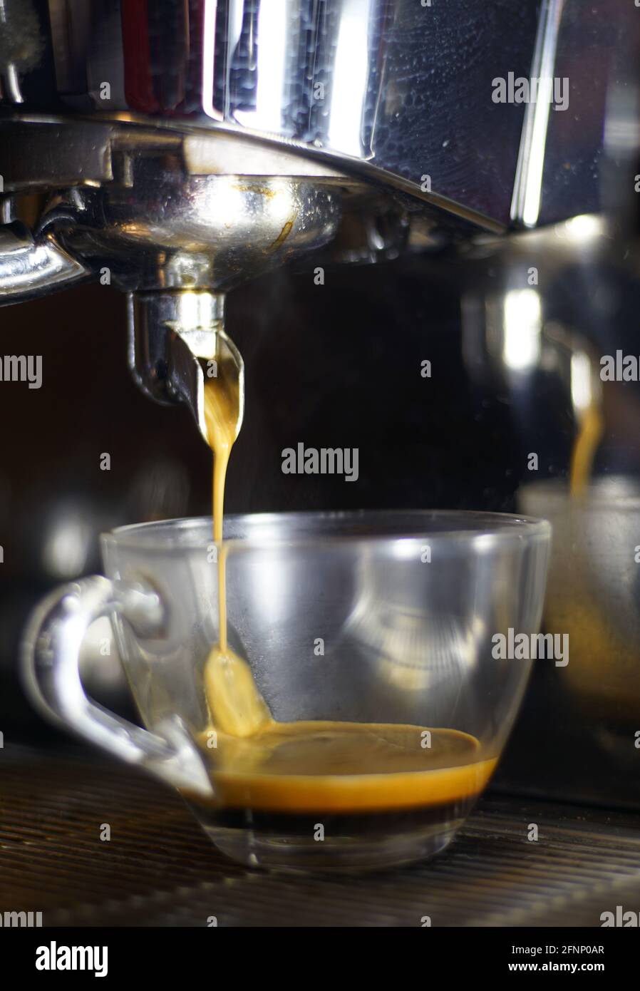 Vertical closeup of an espresso machine pouring fresh coffee in a cup ...