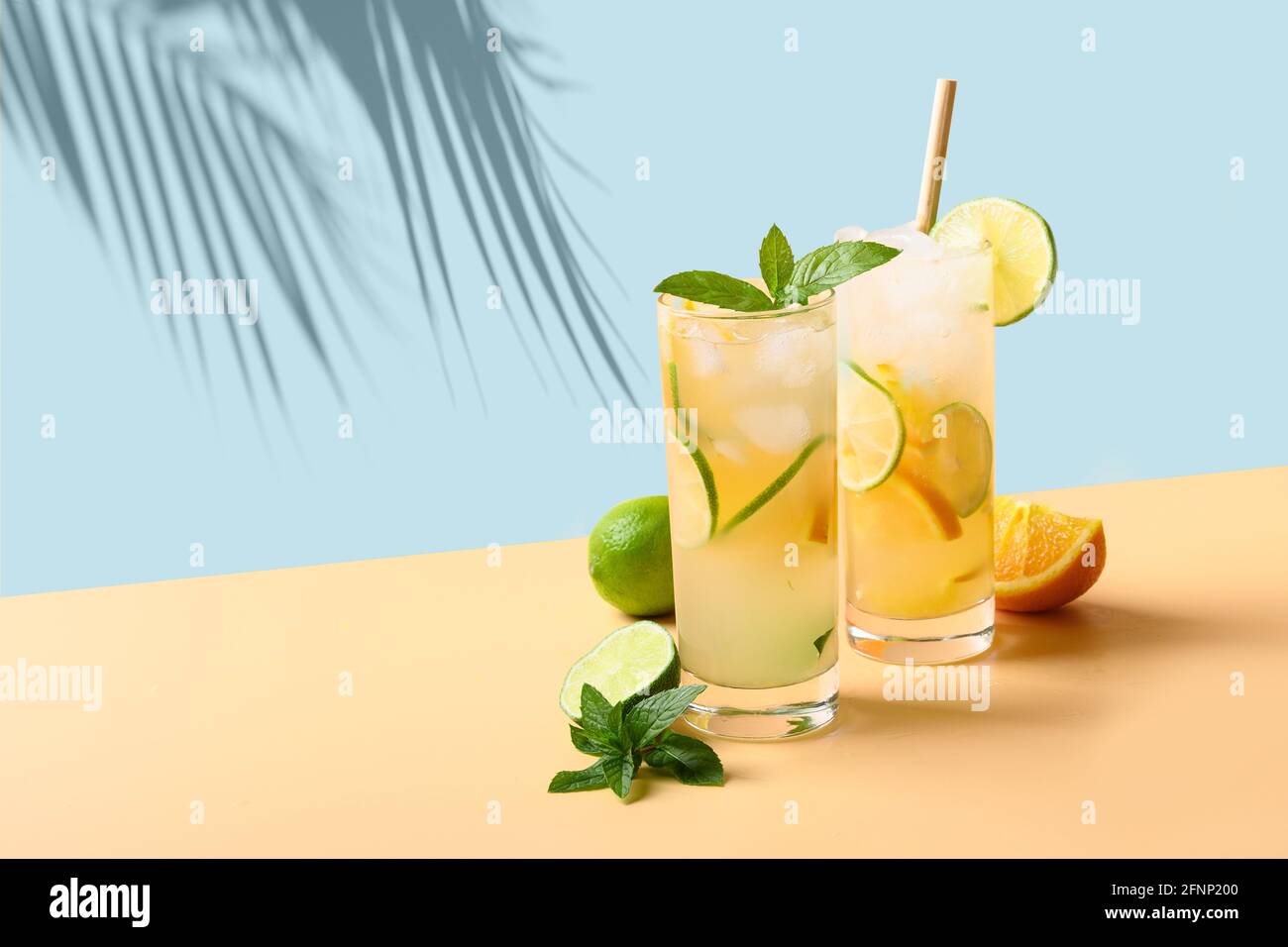 Two summer cold mojito cocktails with orange and lime slices on blue ...